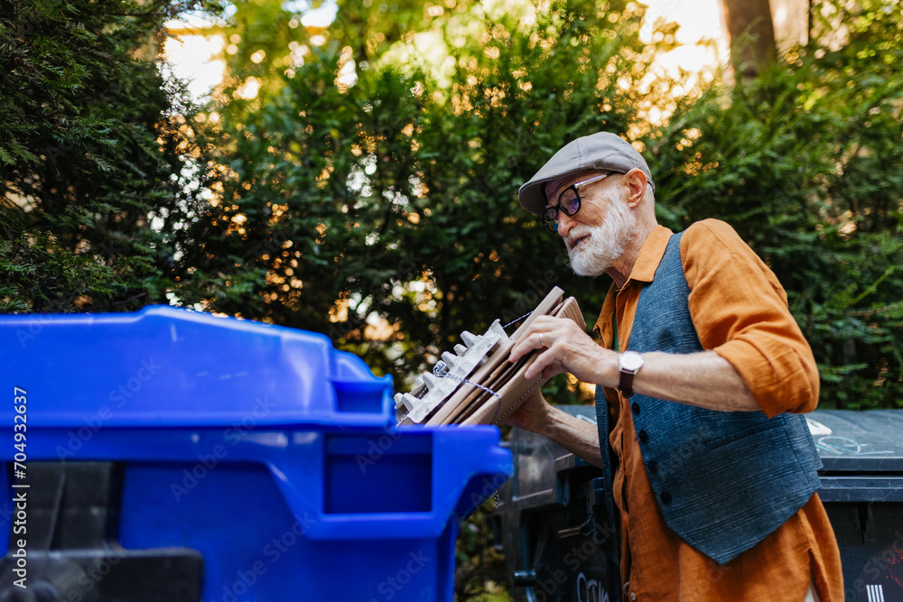 Senior man throwing paper waste, cardboards into recycling container in ...