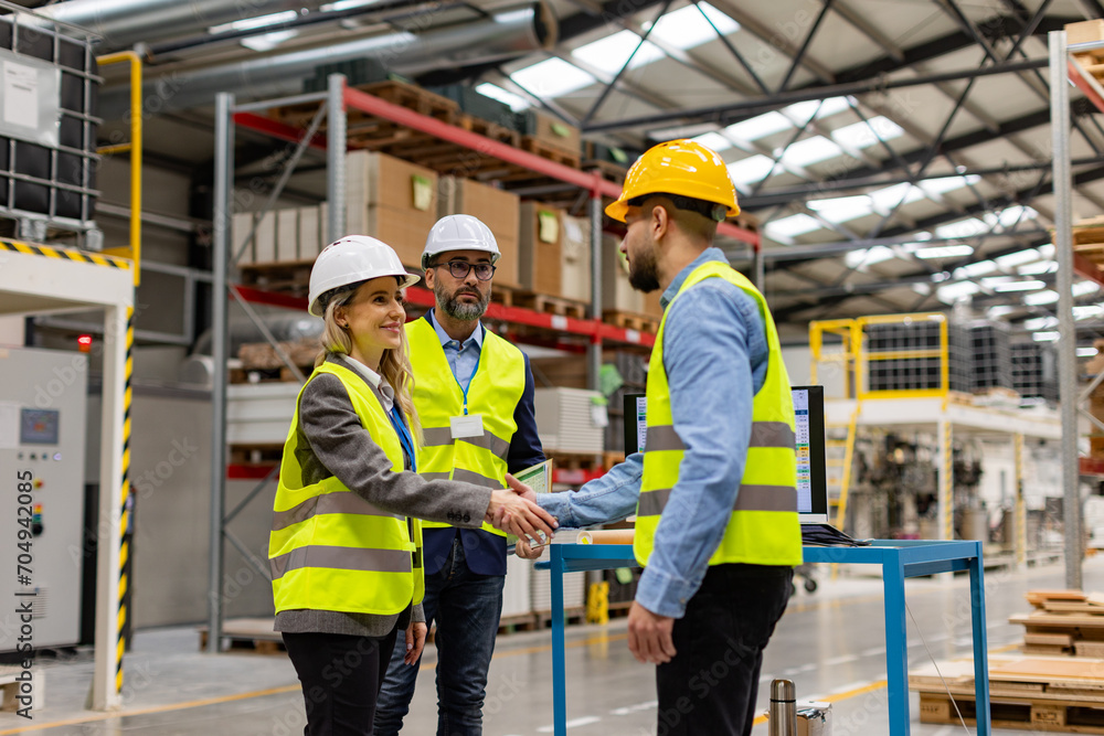 Engineers shaking hands with foreman in modern industrial factory ...