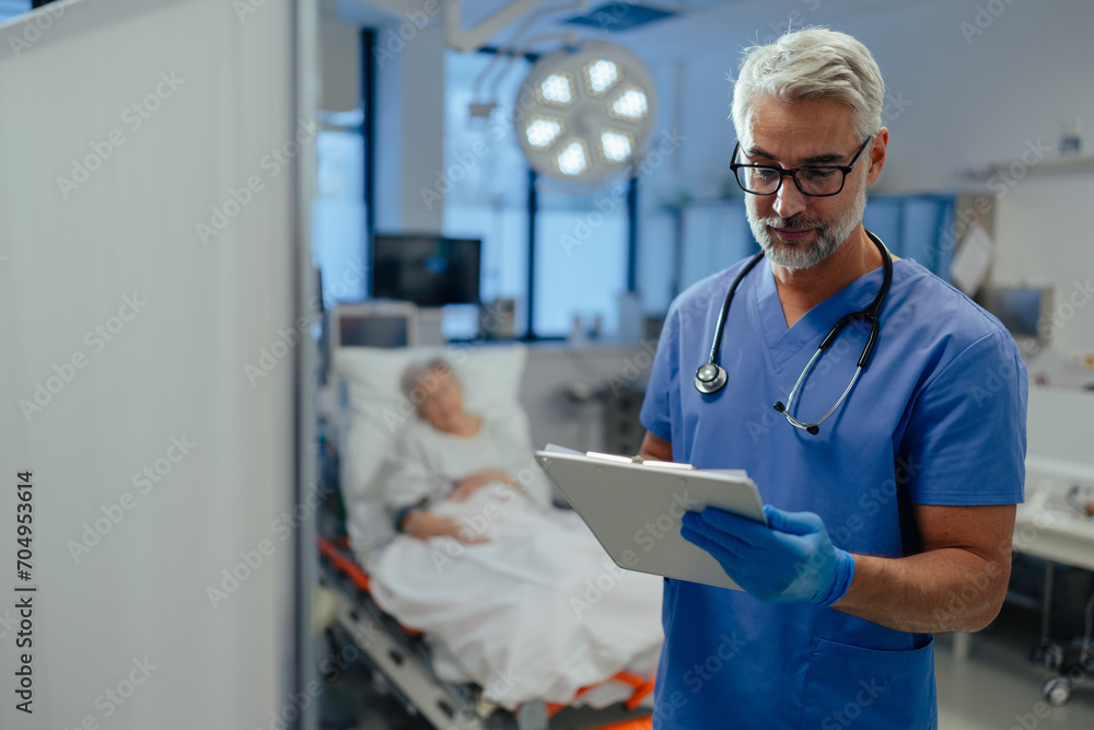 Portrait of handsome male doctor, patient in hospital bed behind. ER ...