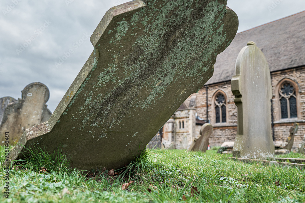 Shallow focus of a stone grave seen heavily leaning over due to ground ...