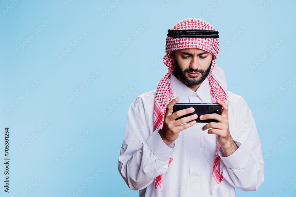 Arab man dressed in traditional attire enjoying leisure activity while ...