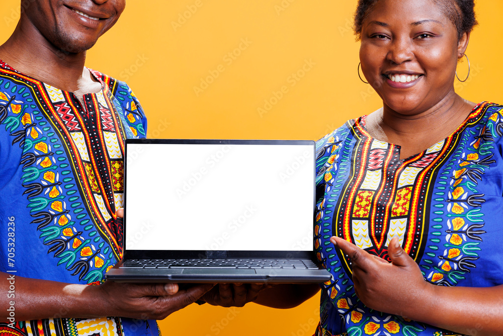 Cheerful black couple holding laptop together and pointing with finger ...