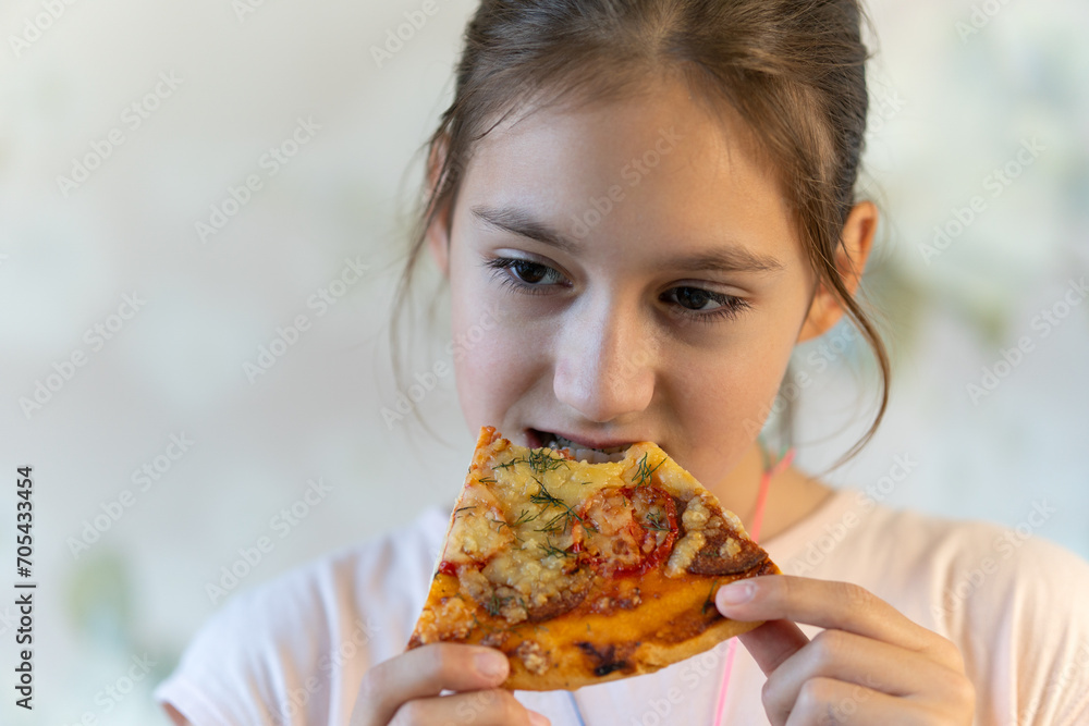 little girl keeps slice of pizza in mouth, spreads hands with ...
