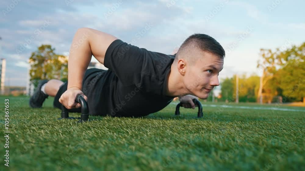 Guy exercising outdoors, he does push-ups on the push-up platform at ...