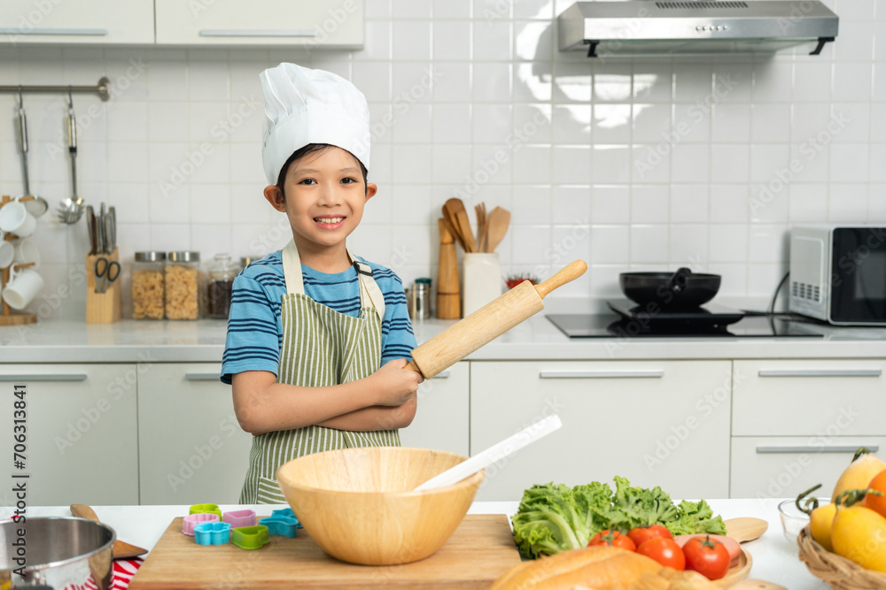 Asian Little chef boy cooking breakfast in the kitchen. Funny kids are ...
