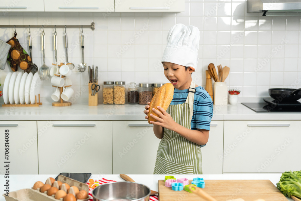 Asian Little chef boy cooking breakfast in the kitchen. Funny kids are ...