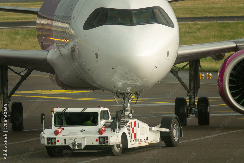 Tow tractor pushes the passenger airplane. Pushback tractor with ...