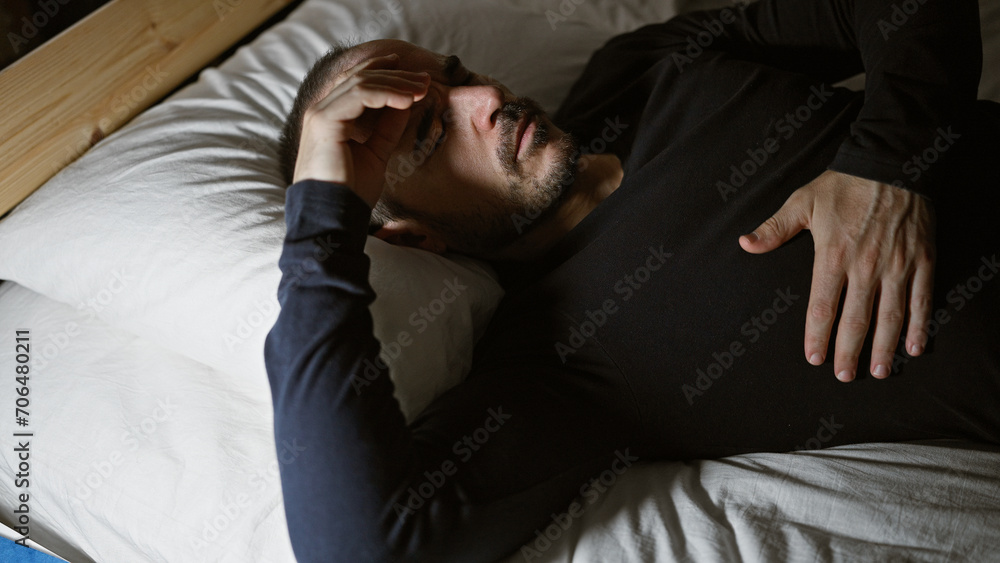Photo & Art Print A bearded, bald hispanic man lying in bed with a ...