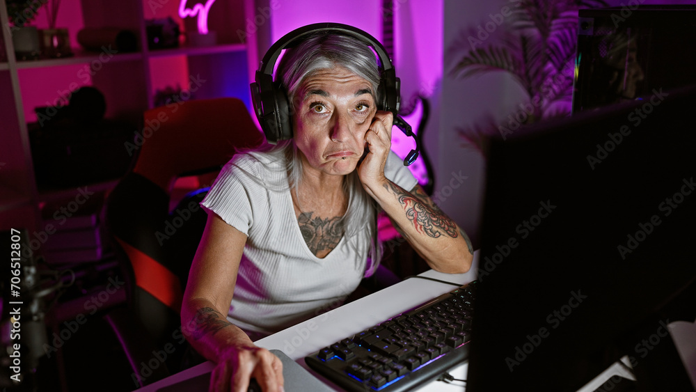 Mature, grey-haired woman gamer, in serious gaming mode, streaming live ...