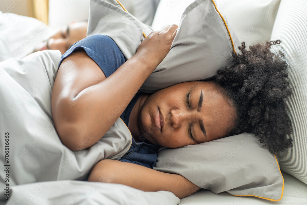 black African American woman covers her ears with a pillow, can't sleep ...
