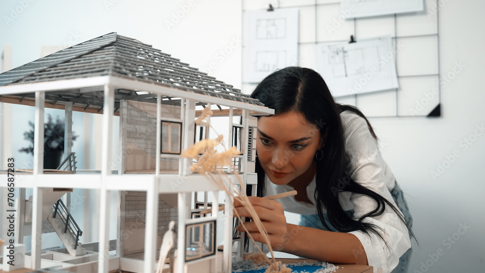 Young beautiful caucasian architect engineer turns house model around ...
