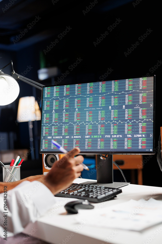 This image shows a pc monitor displaying financial reports while a ...