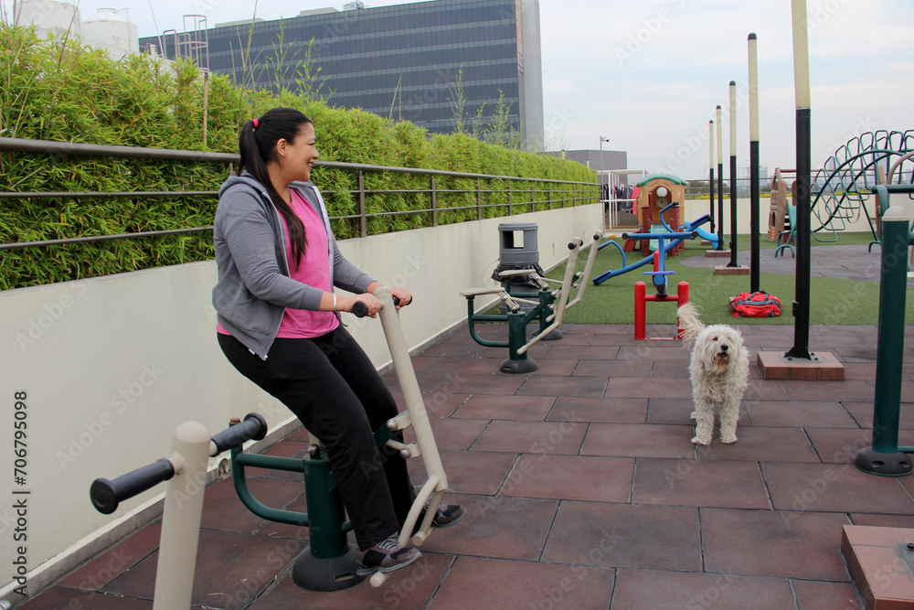Fototapeta 40-year-old Latina woman exercises in the roof garden of her ... Fototapeta 40-year-old Latina woman exercises in the roof garden of her ...