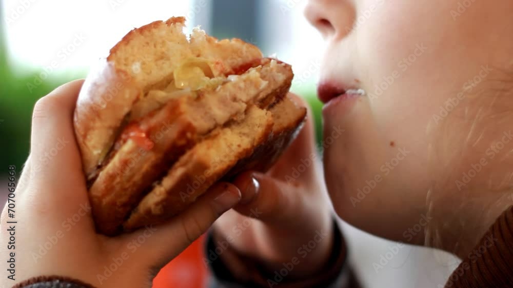 Vidéo Stock Girl eating a hamburger close-up. A child eats a hamburger ...
