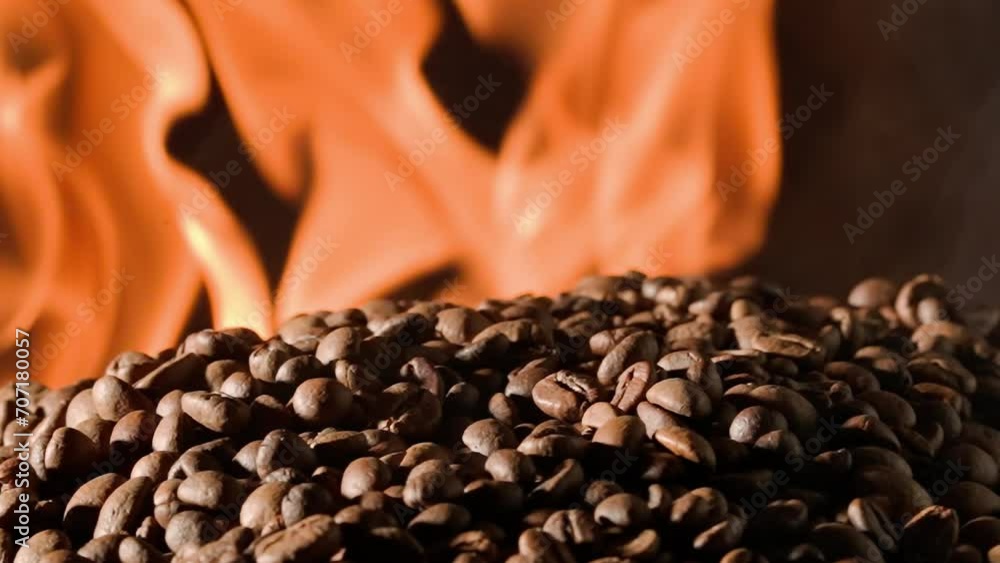 Coffee beans rotate on a black studio background with burning tongues ...