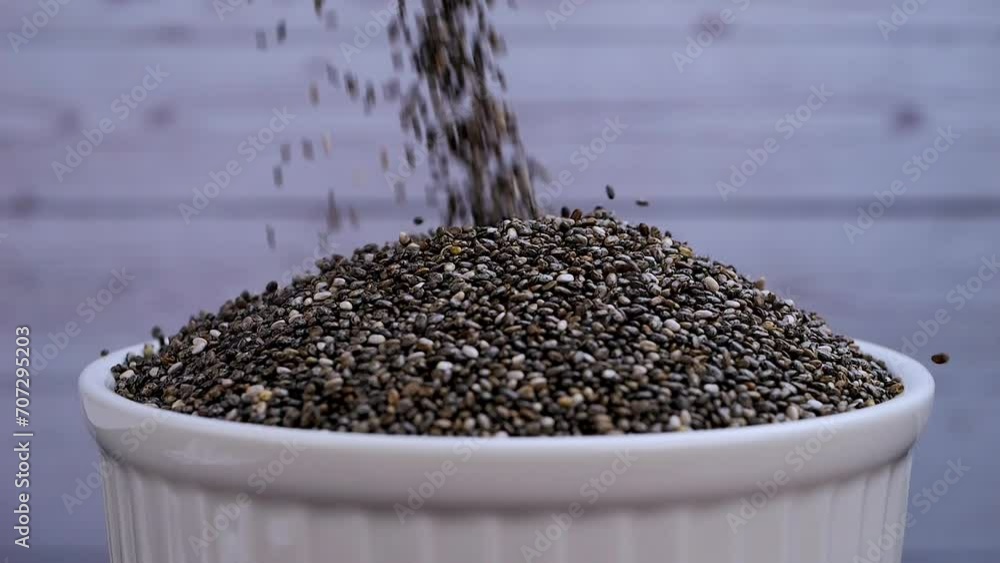 Chia seeds falling into a white bowl in slow motion. Chia seeds are ...