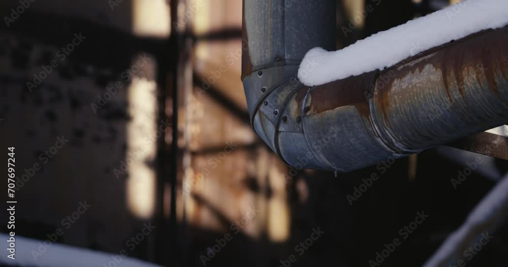 Snowy pipe in an abandoned industrial factory. Rusty metal surfaces in ...