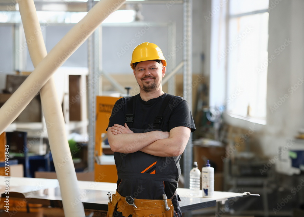 Portrait of young attractive man in work clothes and yellow helmet ...