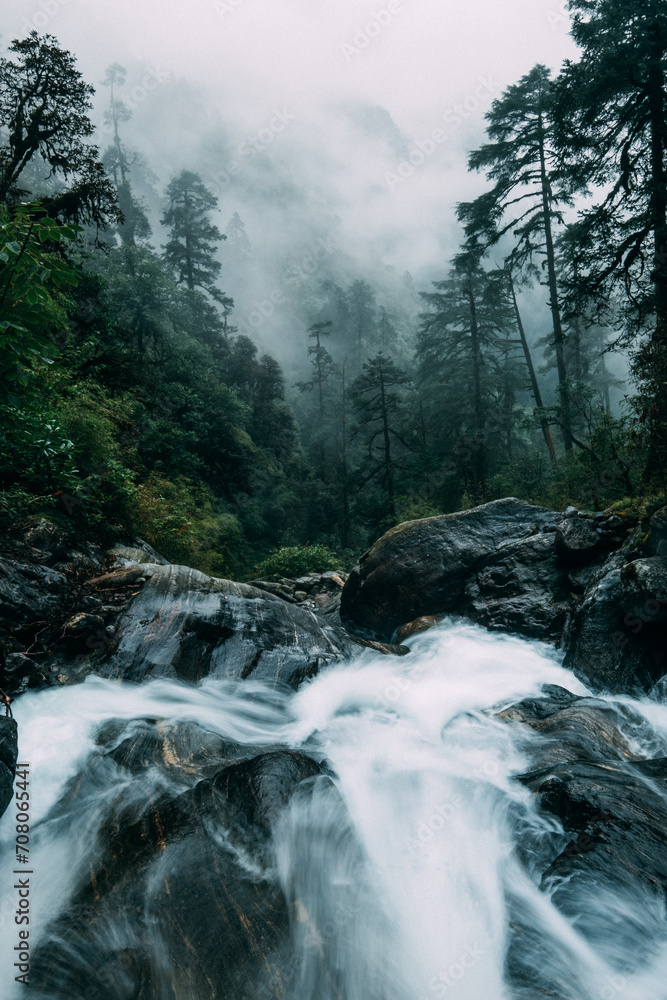Powerful mountain creek running through the big boulders down the foggy ...
