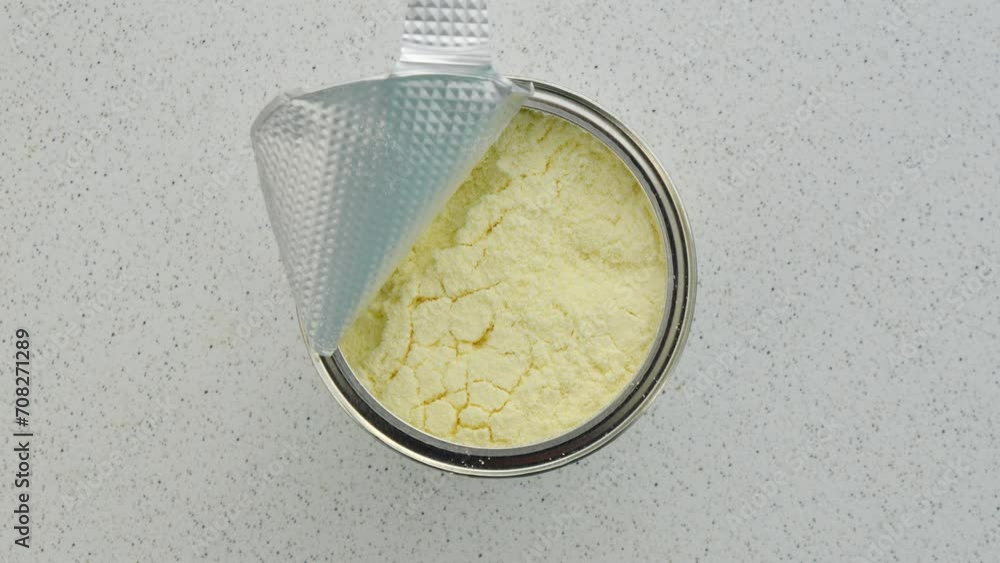 Powdered milk container with open lid, highlighting the fine texture ...