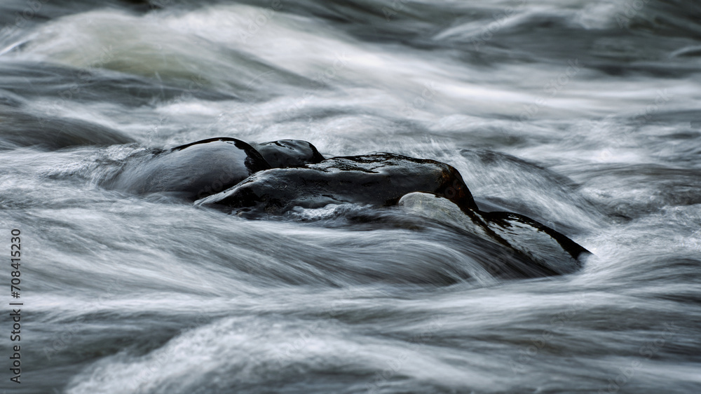 Schwarzer Stein im fließendem Wasser. Strömung umspühlt Steine. Fluß ...