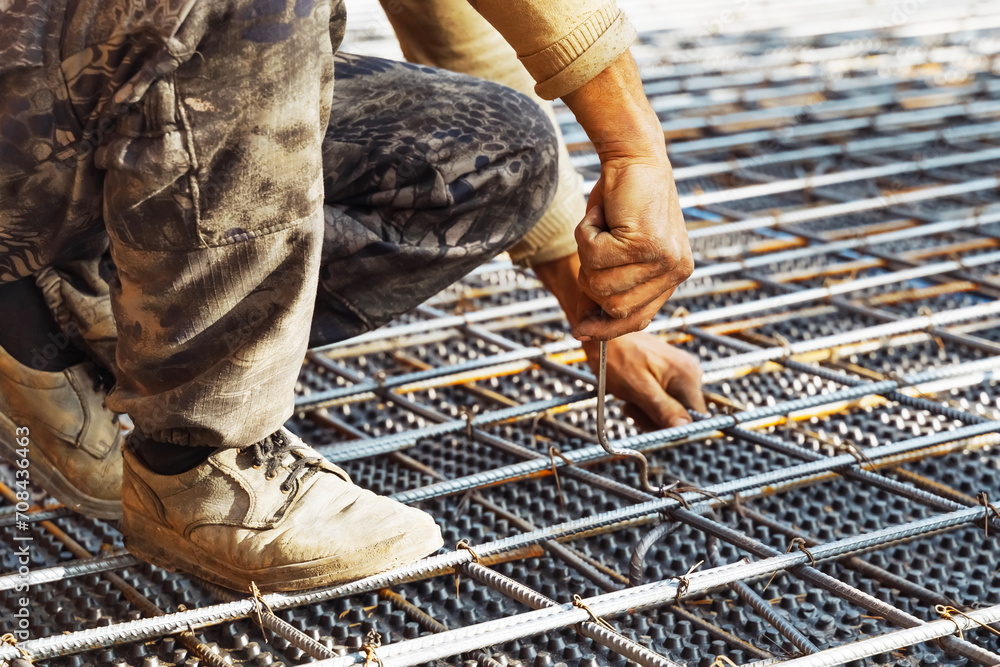 Ironworker securing steel rebar framing at construction site, worker ...