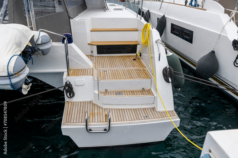 Stern of super luxury yacht berthed in marina. Teak deck on stern of ...