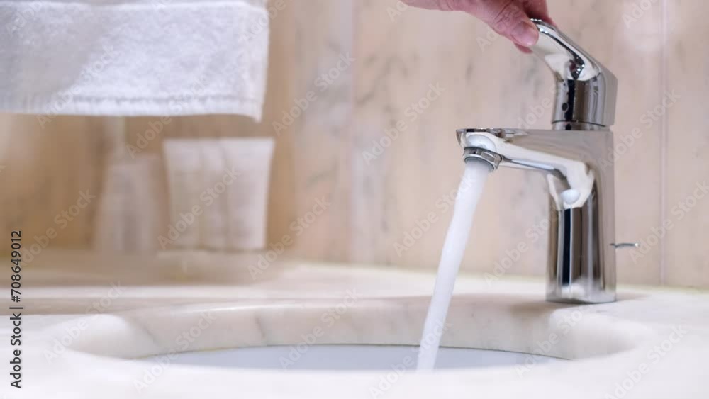 Close-up slow motion of caucasian female hand opening a mixer tap in a ...