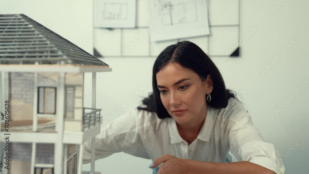 Young beautiful caucasian architect engineer turns house model around ...