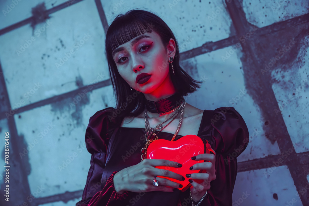 Gothic fashion model clutching a bright red heart, a bold statement ...
