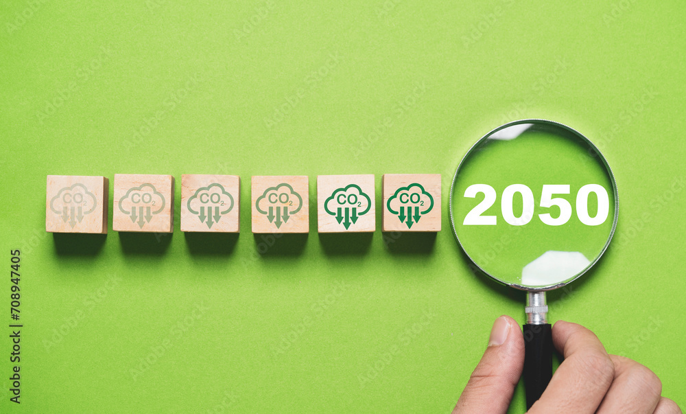 Hand holding magnifier glass with 2050 and CO2 reducing icon for ...