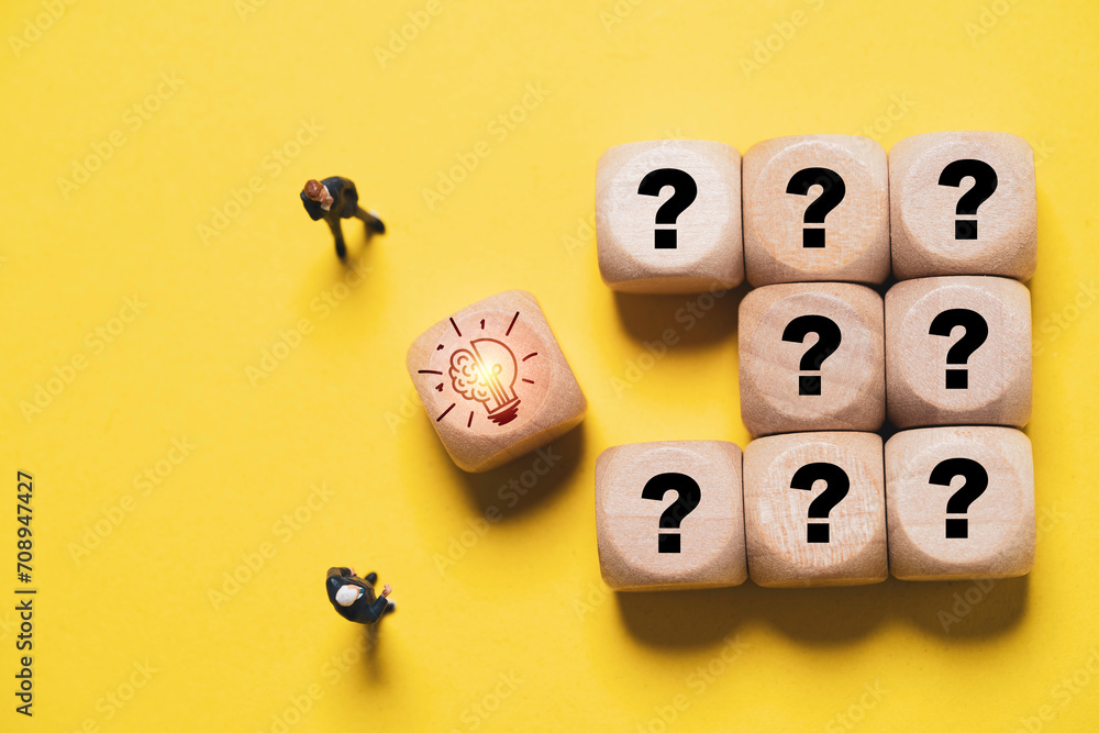 Two miniature businessmen standing and consider with glowing lightbulb ...