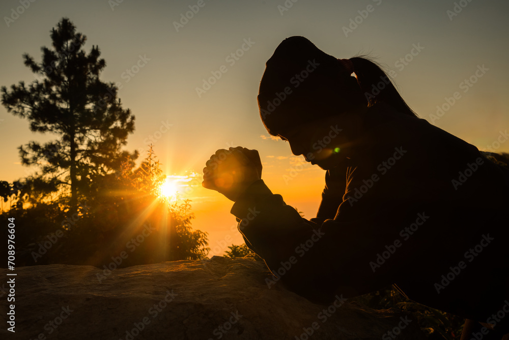 Silhouette of woman kneeling down praying for worship God at sky ...