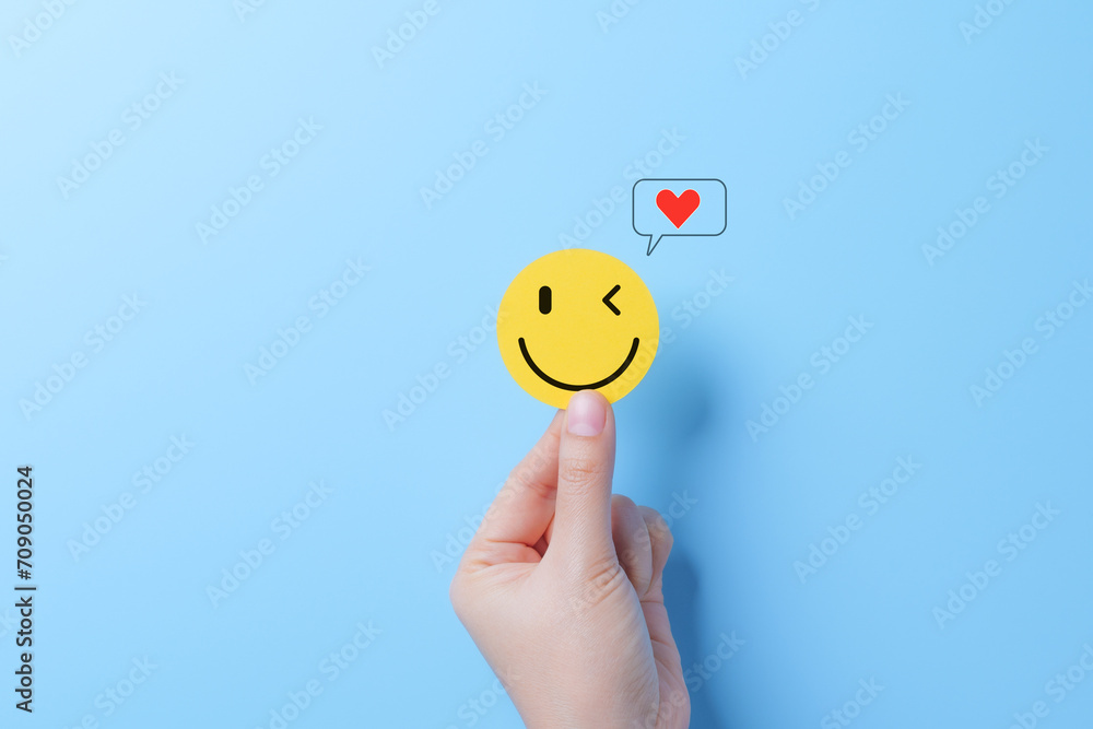 Mental Health Day concept. Hand holding a smiley face icon that depicts ...