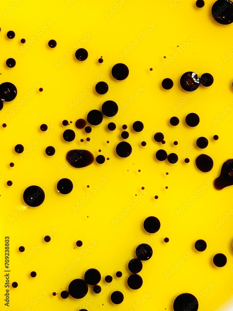texture of the black bubbles and streaks on yellow background. closeup ...