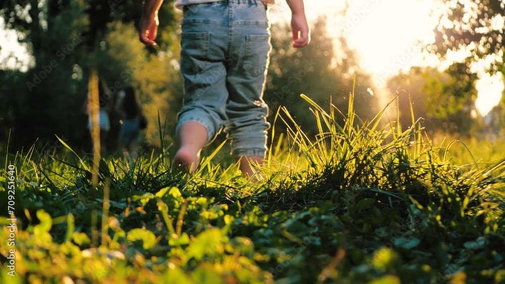 Little contented child joyfully dashes barefoot on grass in park during ...