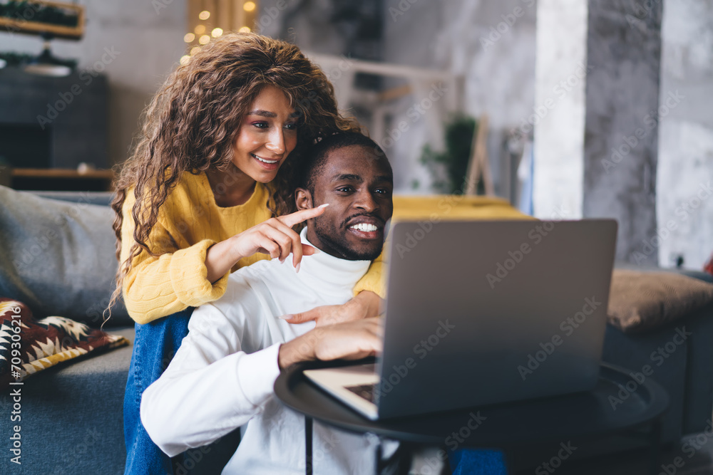Radiant African-American woman points at laptop computer screen ...