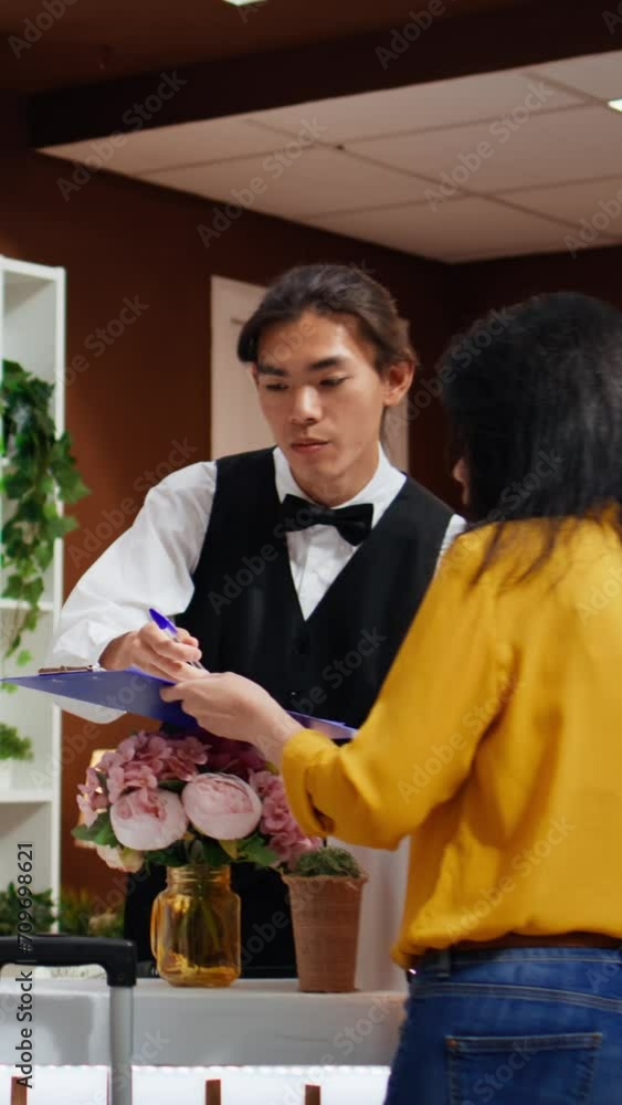 Vertical Video Front desk staff assisting women with registration ...