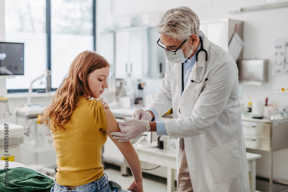Doctor, pediatrician injecting vaccine into teenage girl arm. Concept ...