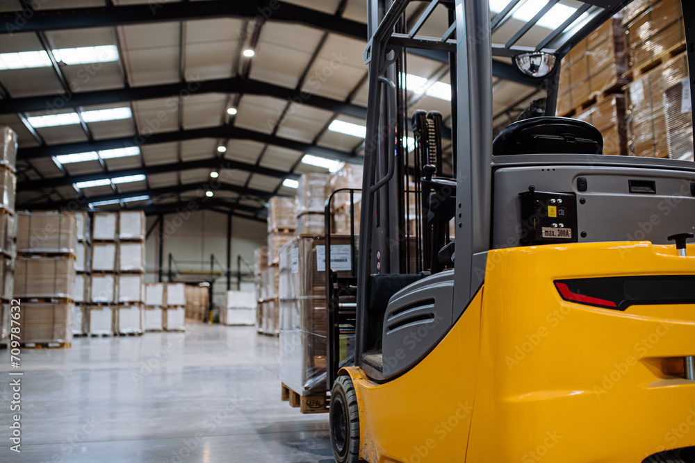Back view of forklift in warehouse in the middle of stored goods ...