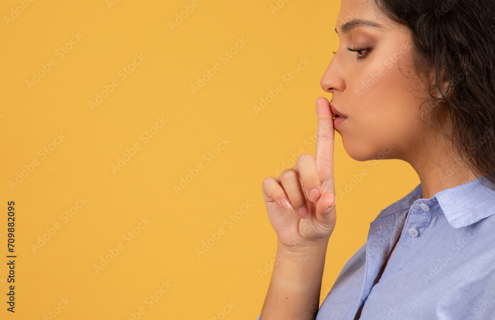 Side profile of a young woman with curly hair placing her index finger ...