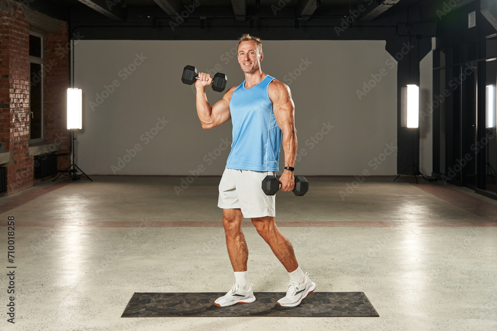An athlete with a strong body and burning eyes performs exercises. His ...