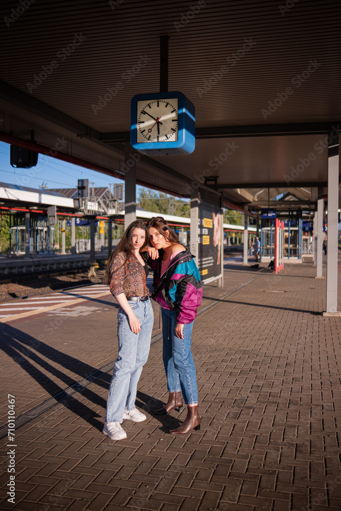 Two beautiful girls dressed in 90s style posing on the platform of the ...