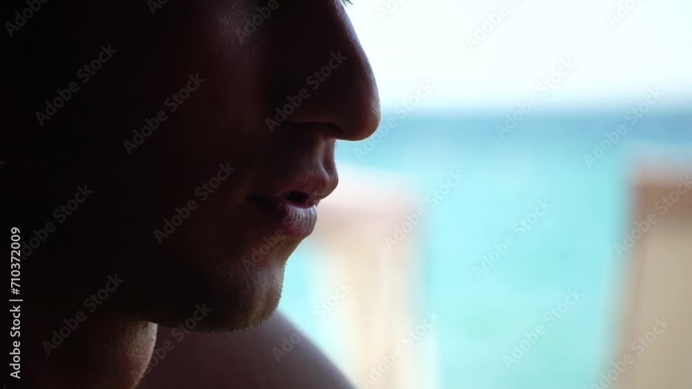 Young, happy man eats sandwich with cheese, sausage and ketchup on ...