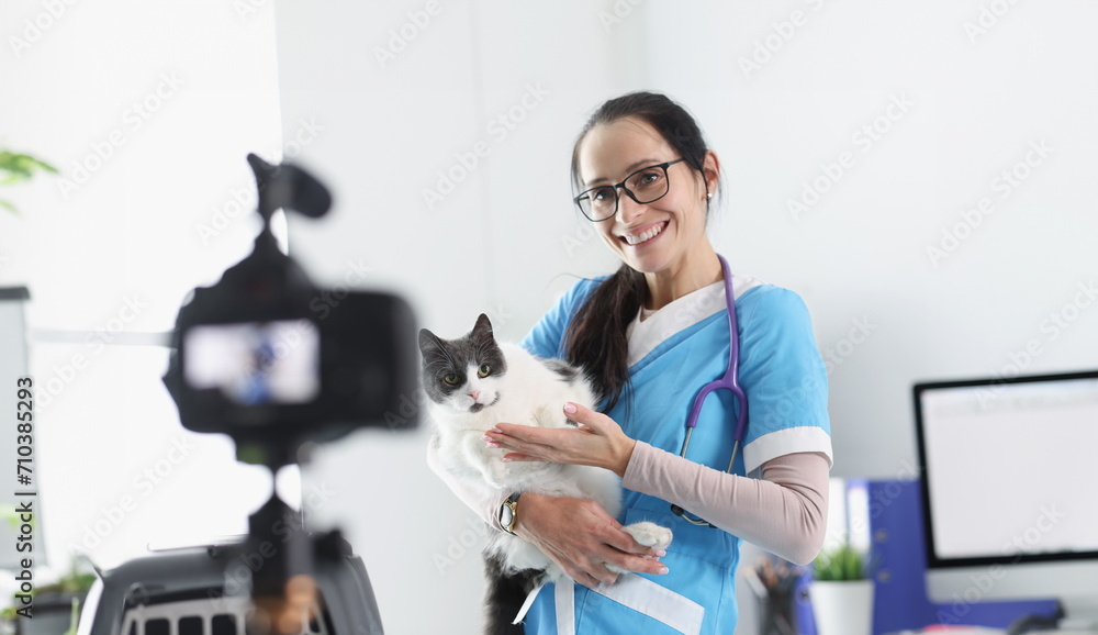 Smiling veterinarian doctor demonstrates cat to camera. Pet care and ...