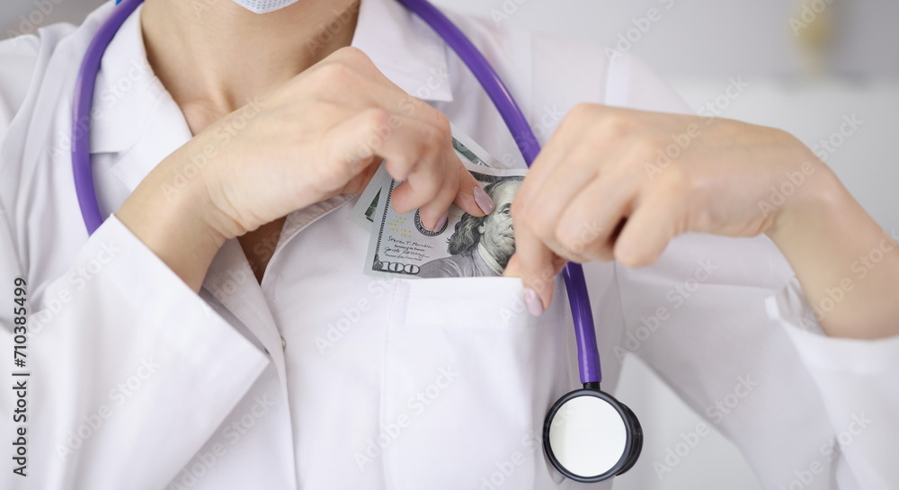 Doctor puts hundred dollar bill in his pocket. Medical scam and bribery ...