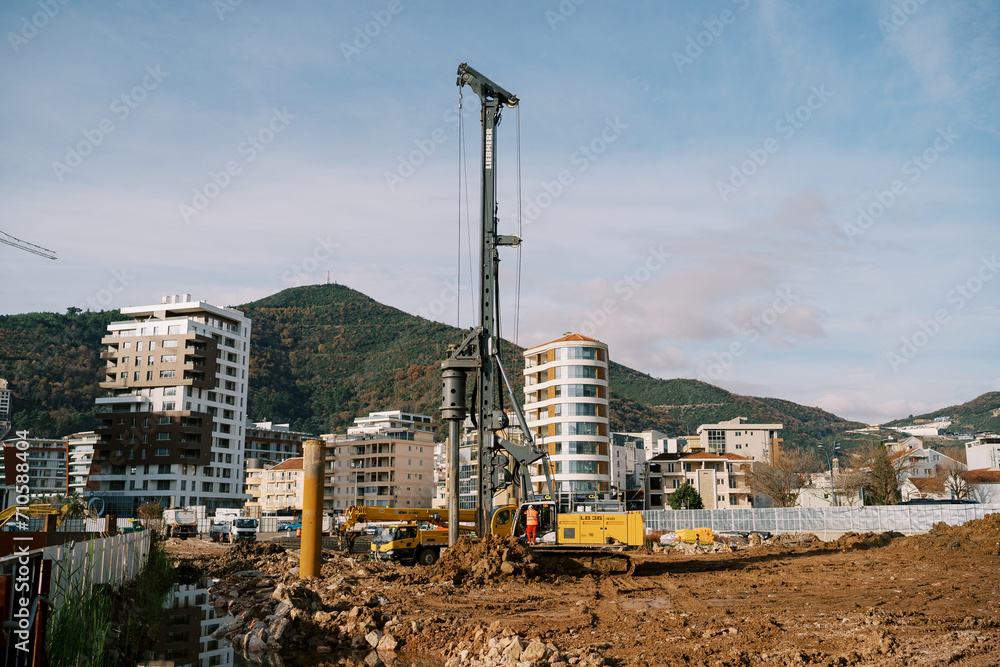 Drilling machine installs piles at a construction site among multi ...