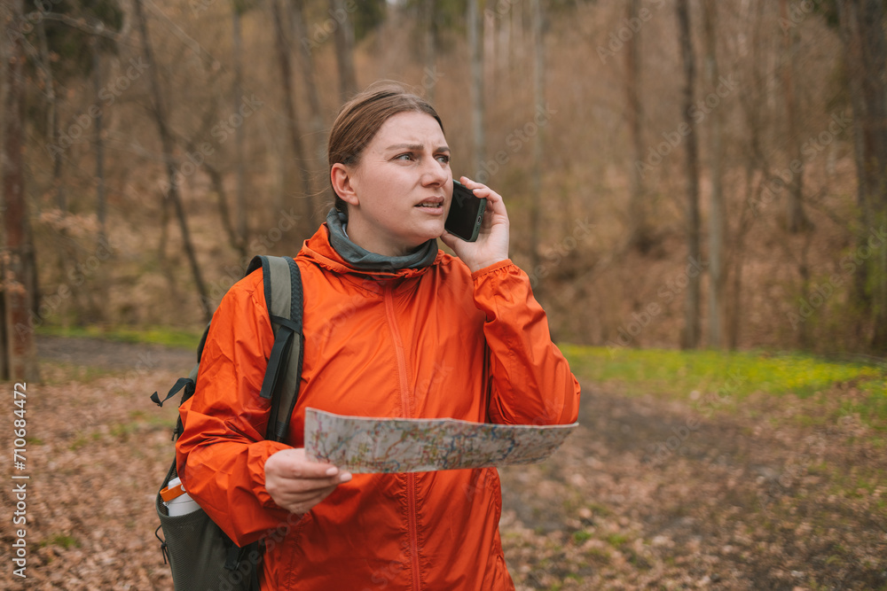 Young lost angry girl in sports clothes with a map in her hands talking ...