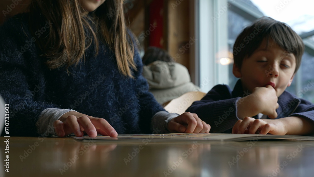Closeup child hand picking food from restaurant menu, young siblings at ...