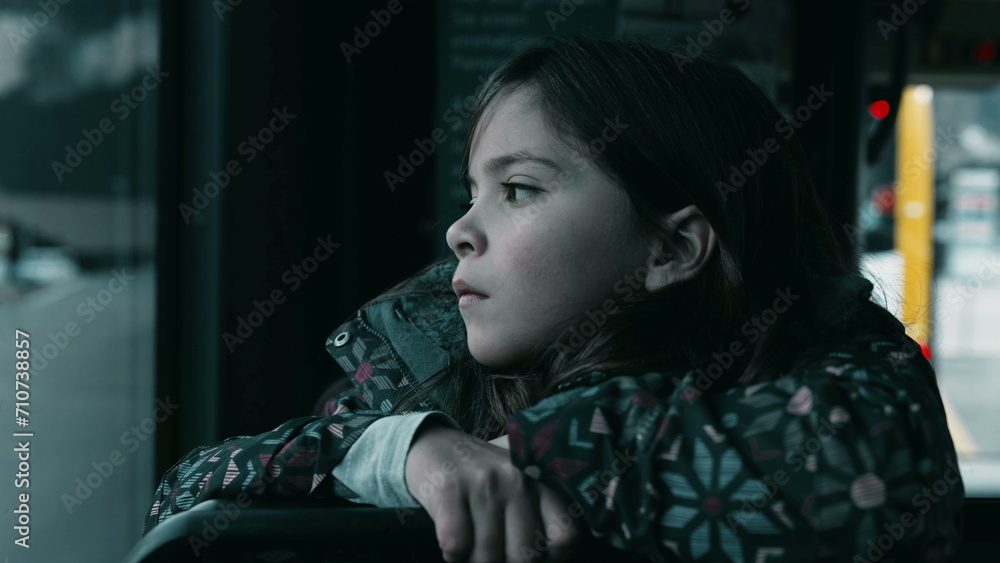 Sad worried little girl staring at view from parked bus, contemplative ...